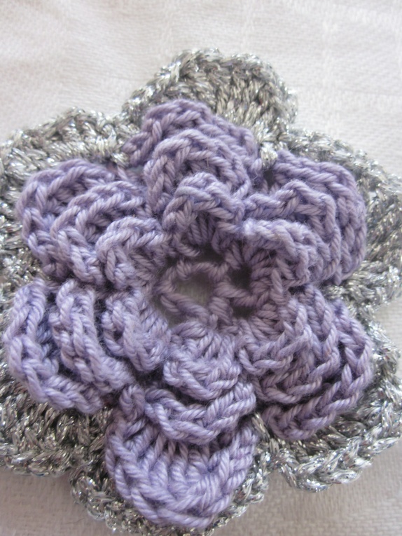Heklet blomst i lys lilla og sølvfarget garn. - Epla